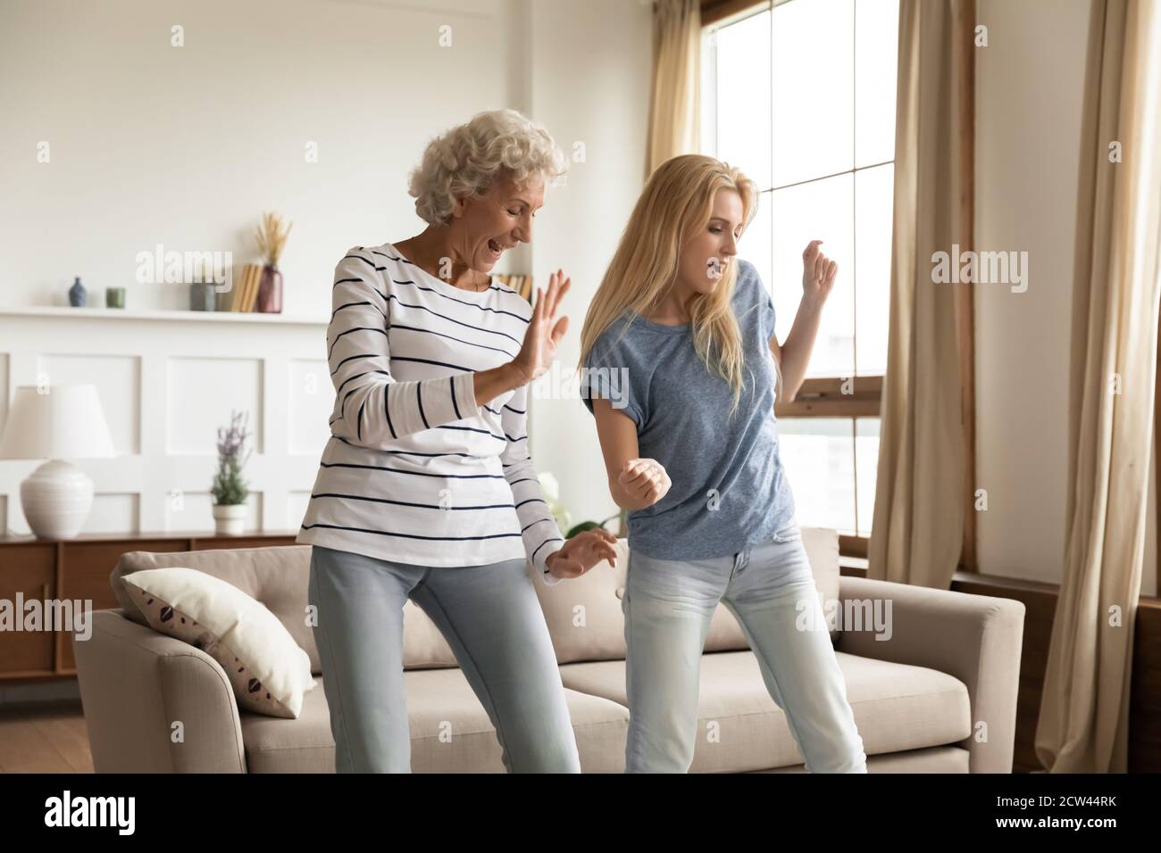 Aged granny and grown granddaughter dancing at home celebrating ...
