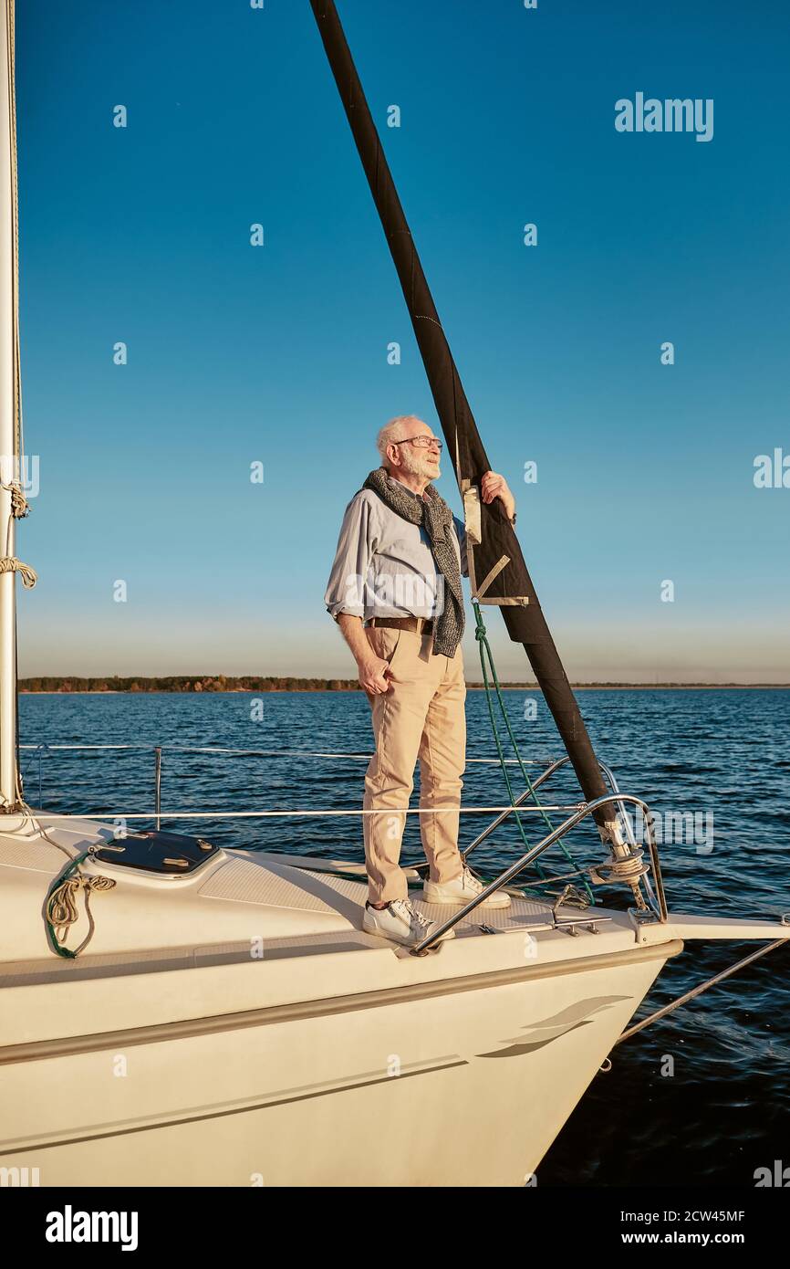 Sailing alone. Vertical shot senior man standing on the side of a ...
