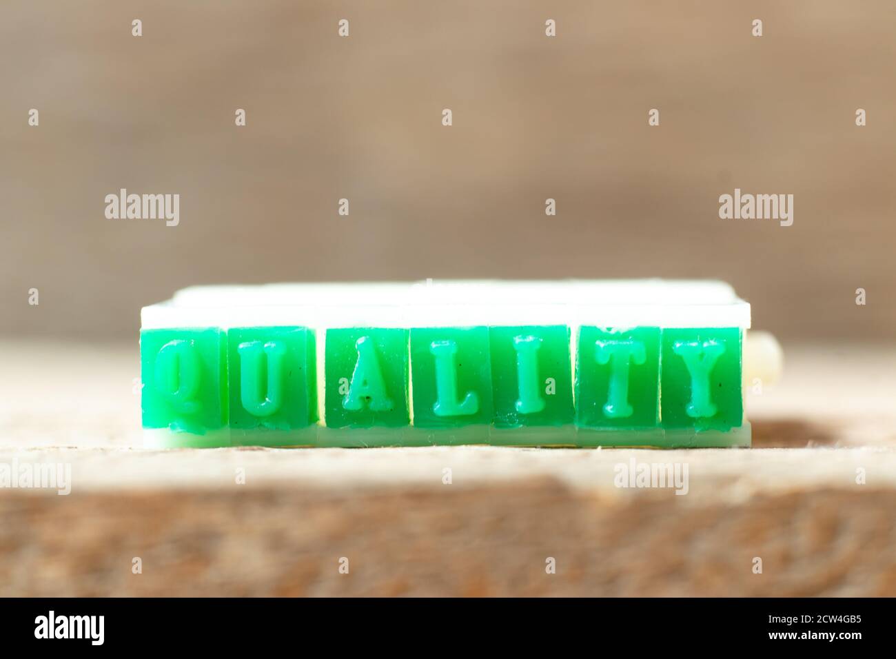 Green color rubber stamp in word quality on wood background Stock Photo ...