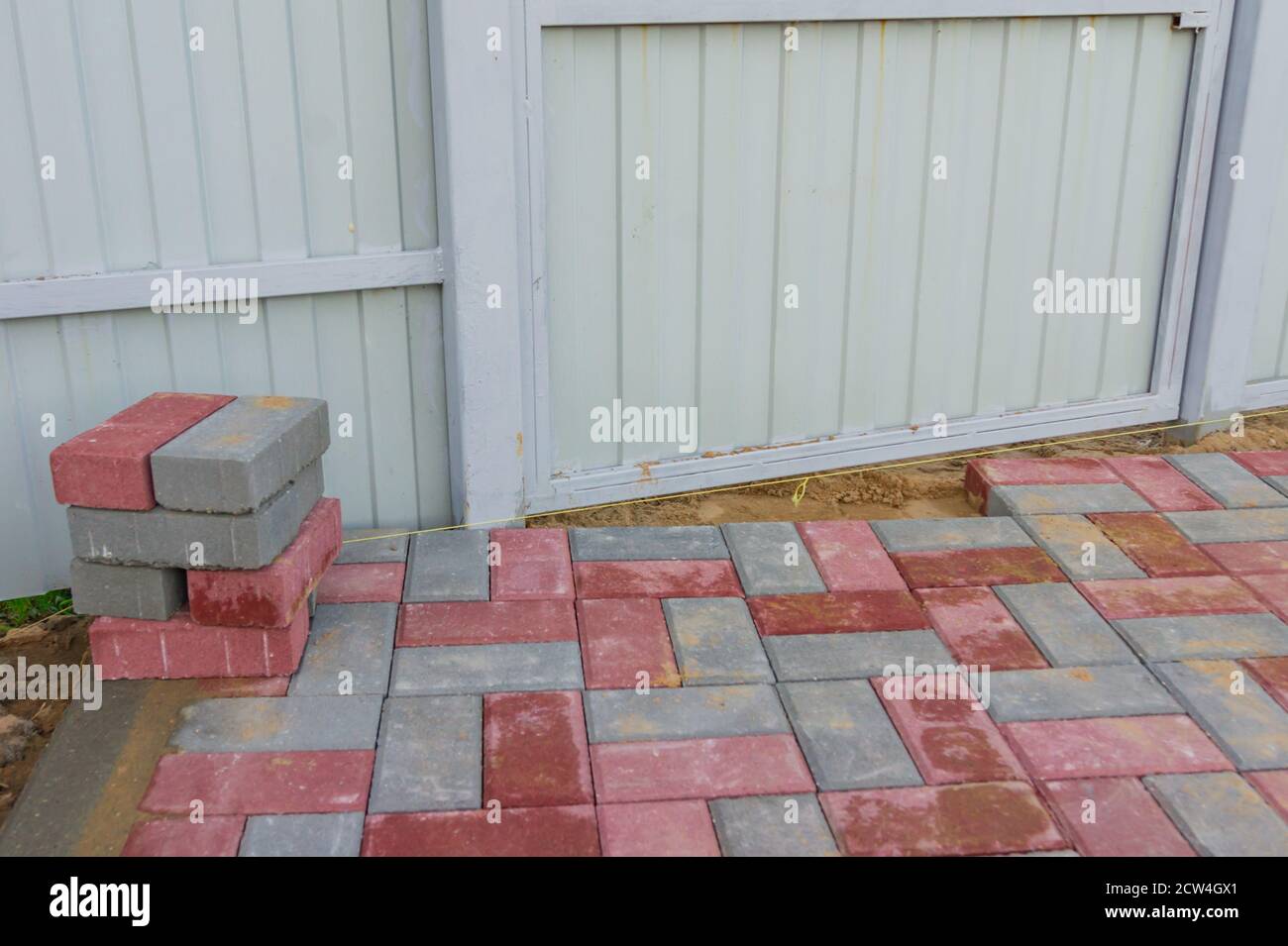 laying red and gray concrete paving blocks on the backyrd. Road Paving ...
