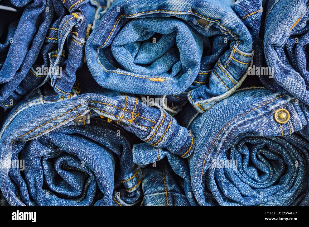 roll blue denim jeans arranged in stack, background texture. Beauty and ...