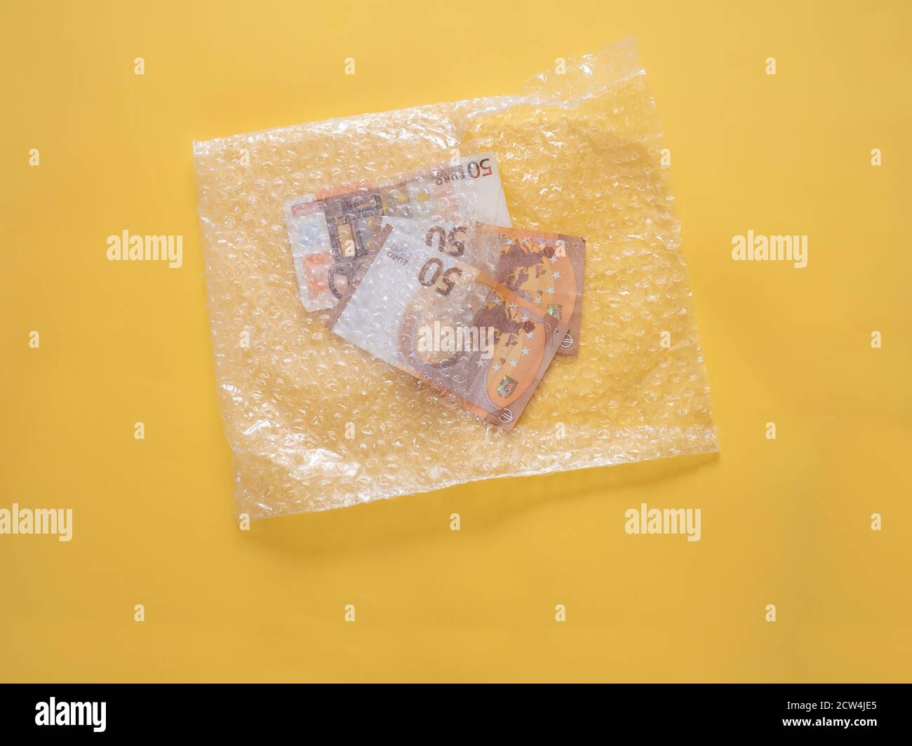 Banknote euros inside a plastic bubbles bag on yellow background ...