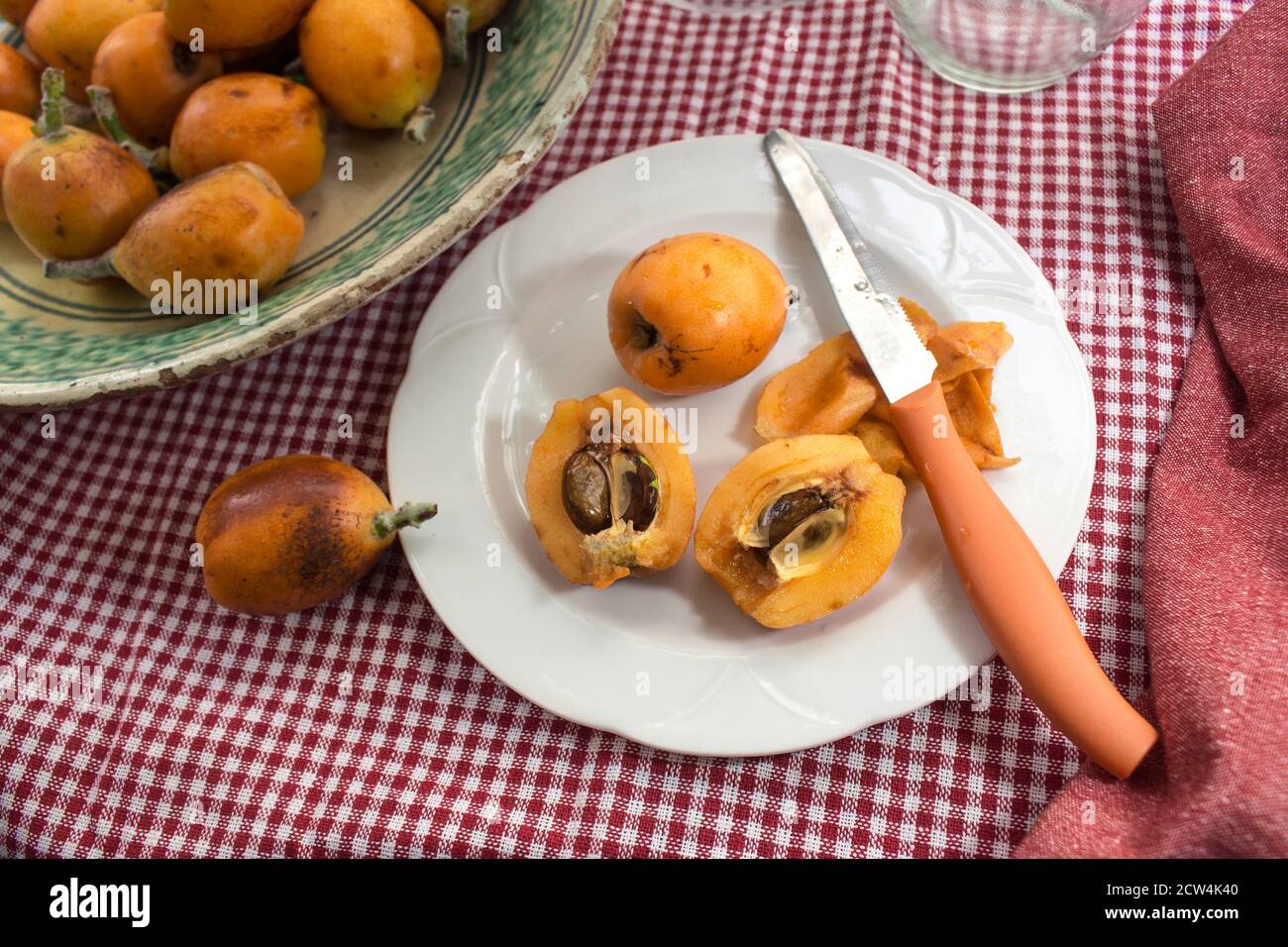 Medlar on a saucer, one of which cut with a knife, on a checkered ...
