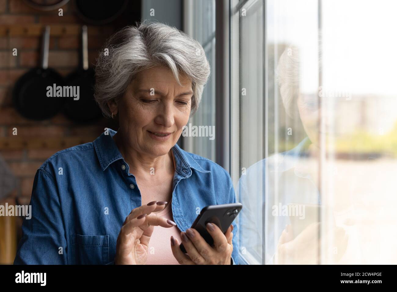 Modern mature woman use smartphone gadget texting Stock Photo - Alamy