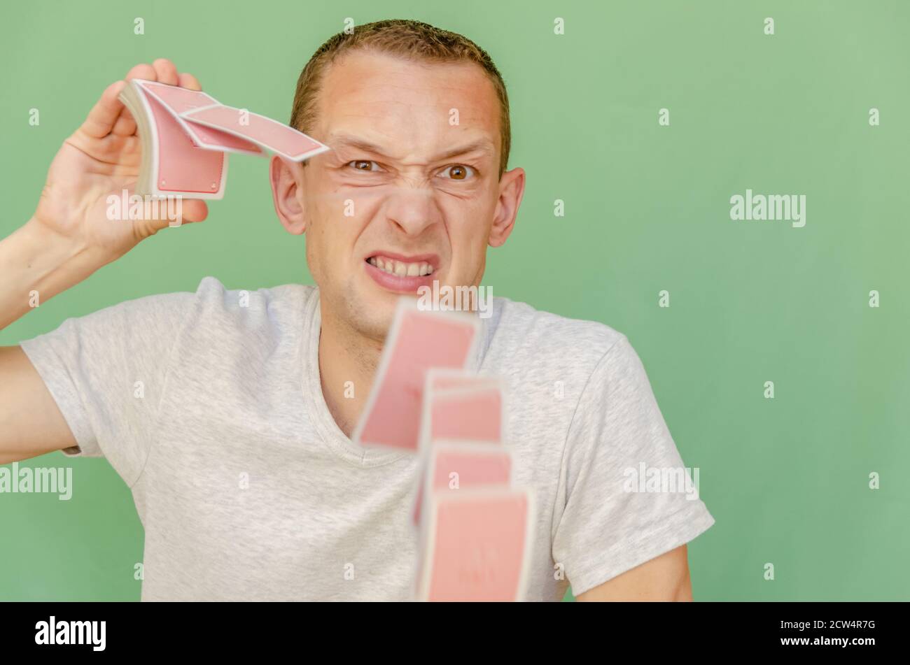 man lost in the cards. he is angry. Throws a fan of cards into the air ...