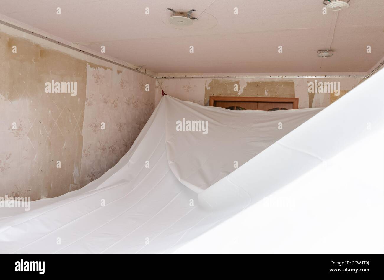 repairmen install stretch ceiling made of pvc vinyl film using a gas ...