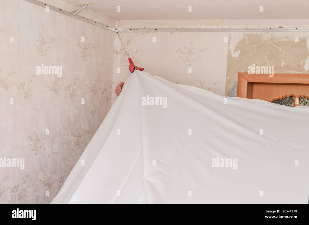 repairmen install stretch ceiling made of pvc vinyl film using a gas ...