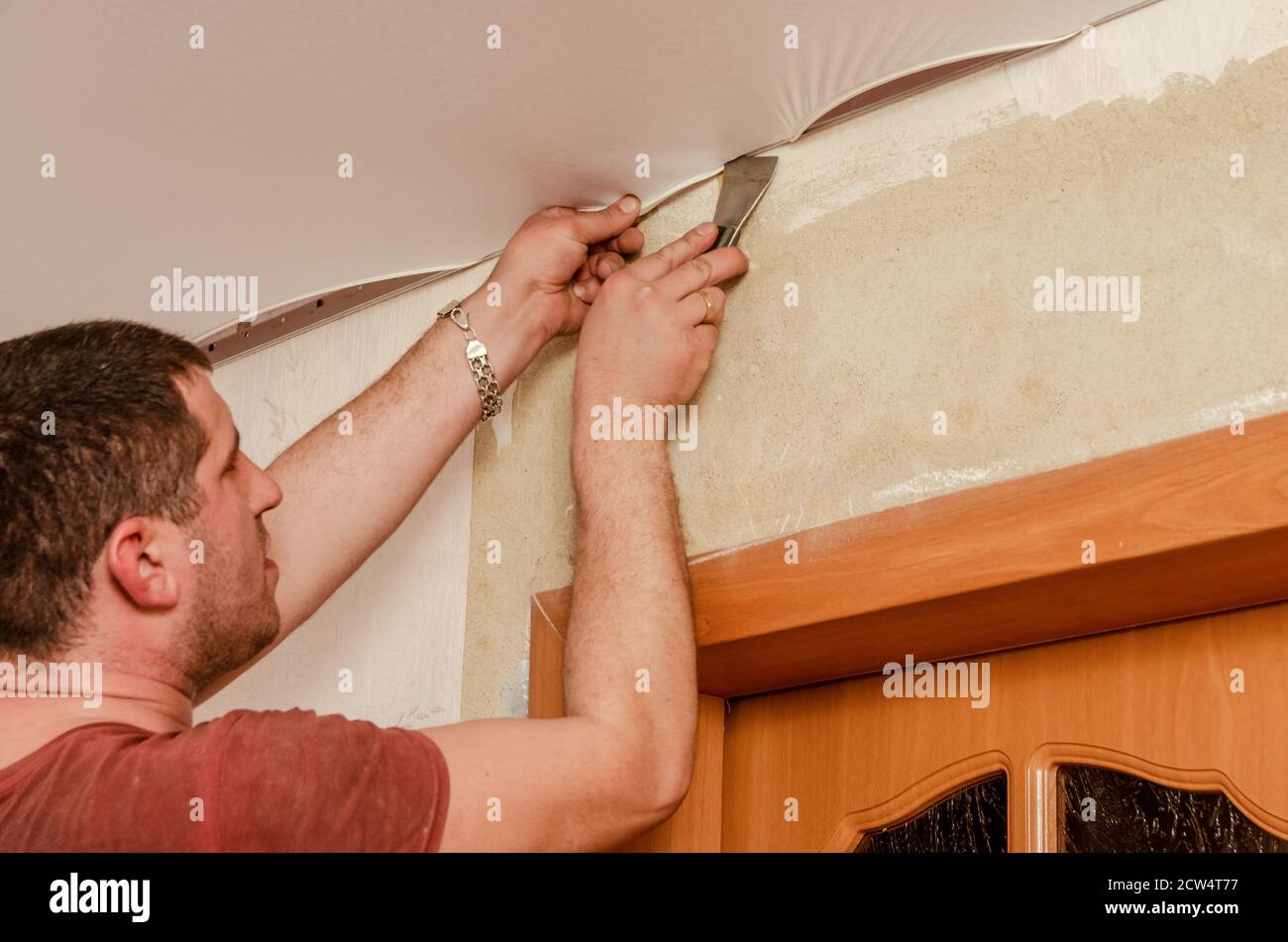 The master installs a stretch ceiling, working on the joints Stock ...