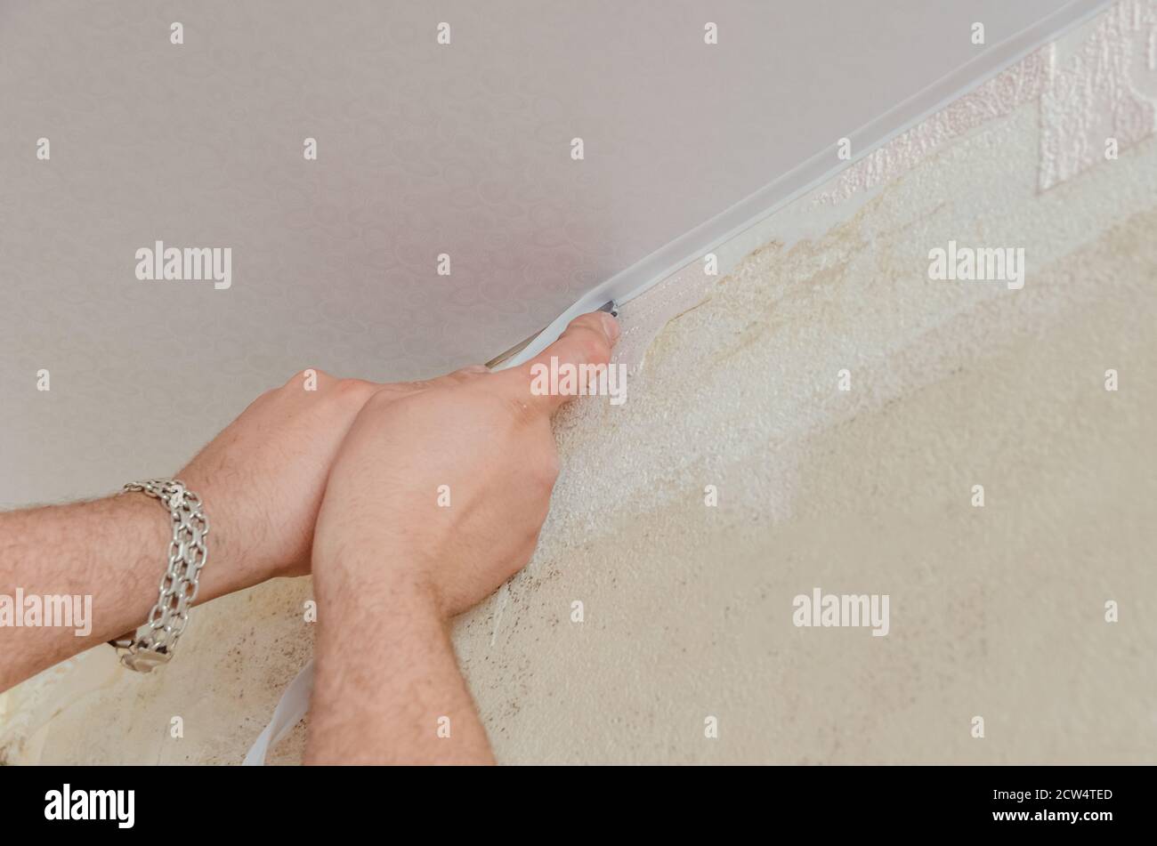 The worker pulls the stretch ceiling in the room, puts the plinth ...