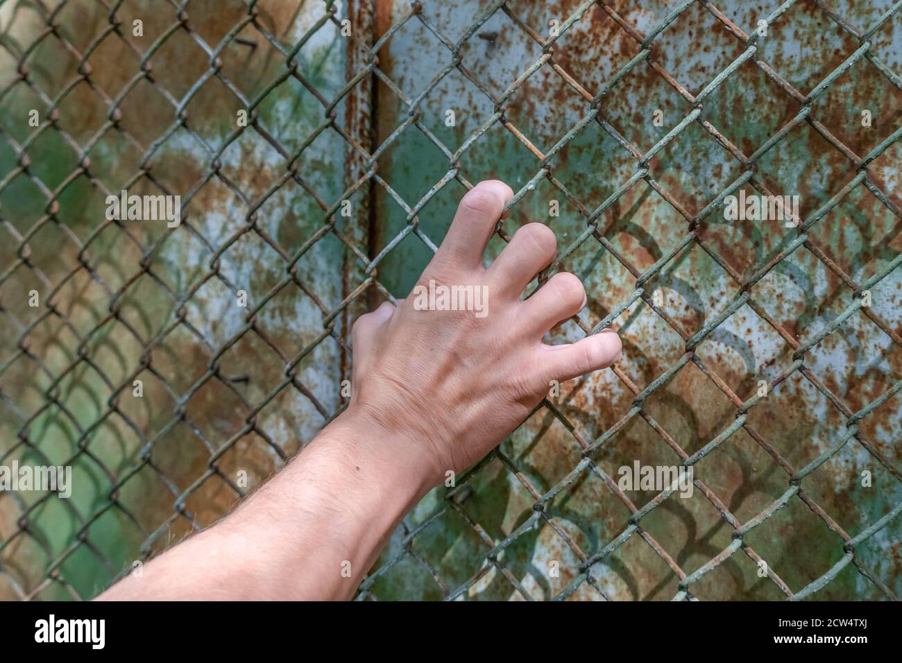 The man's hand on the chain-link fence shows how much he wants to get ...
