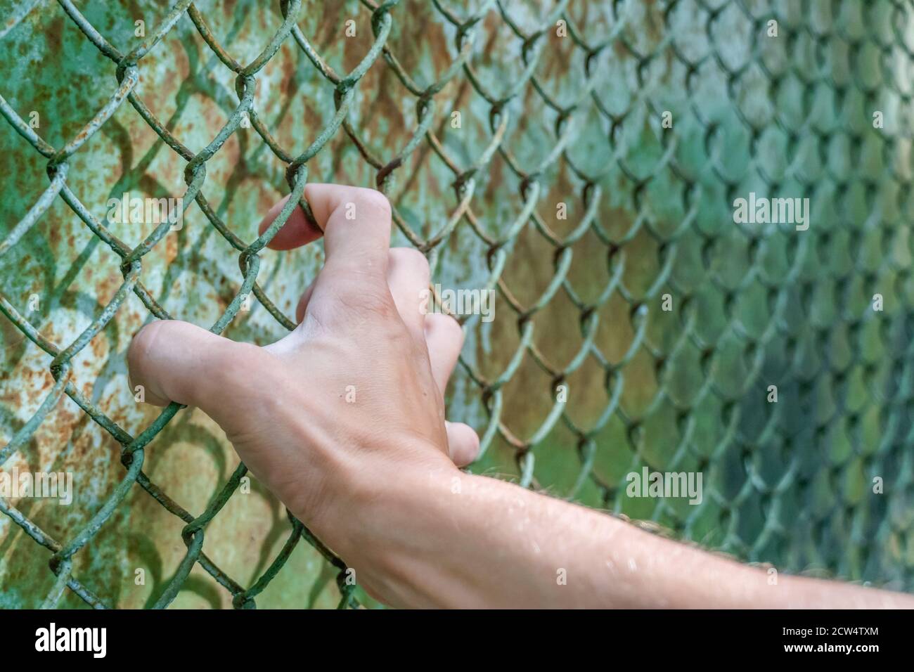 The man's hand on the chain-link fence shows how much he wants to get ...