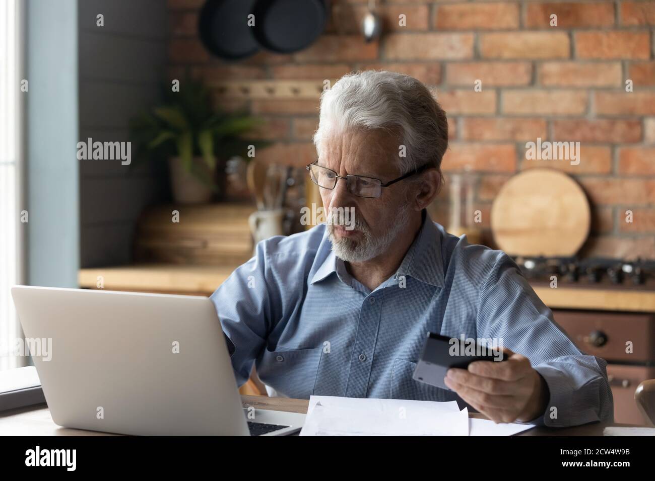 Elderly man look at laptop screen paying bills online Stock Photo - Alamy