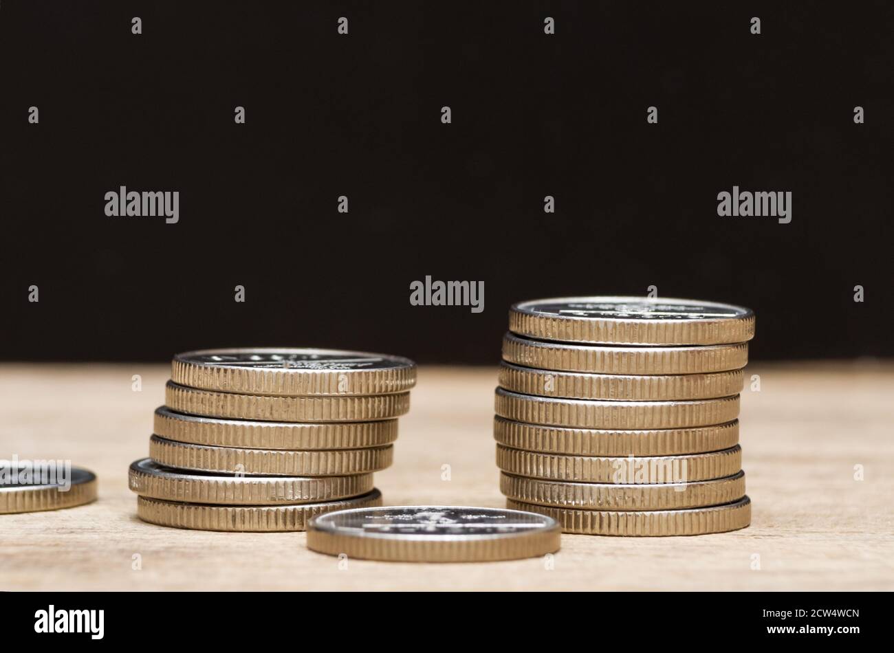 Many euro coins stacked on black background Stock Photo - Alamy