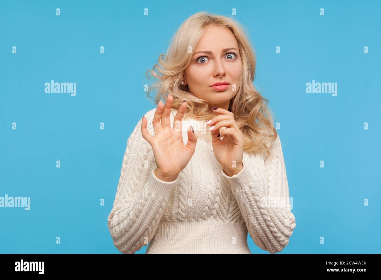 Scared fearful blond woman nervously closing by hands, afraid of ...