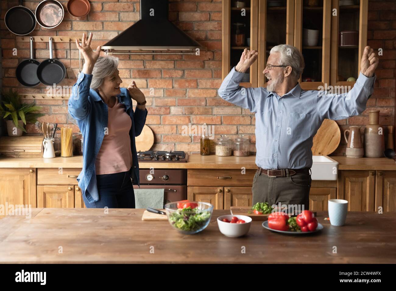Excited healthy senior couple dance cooking together Stock Photo - Alamy