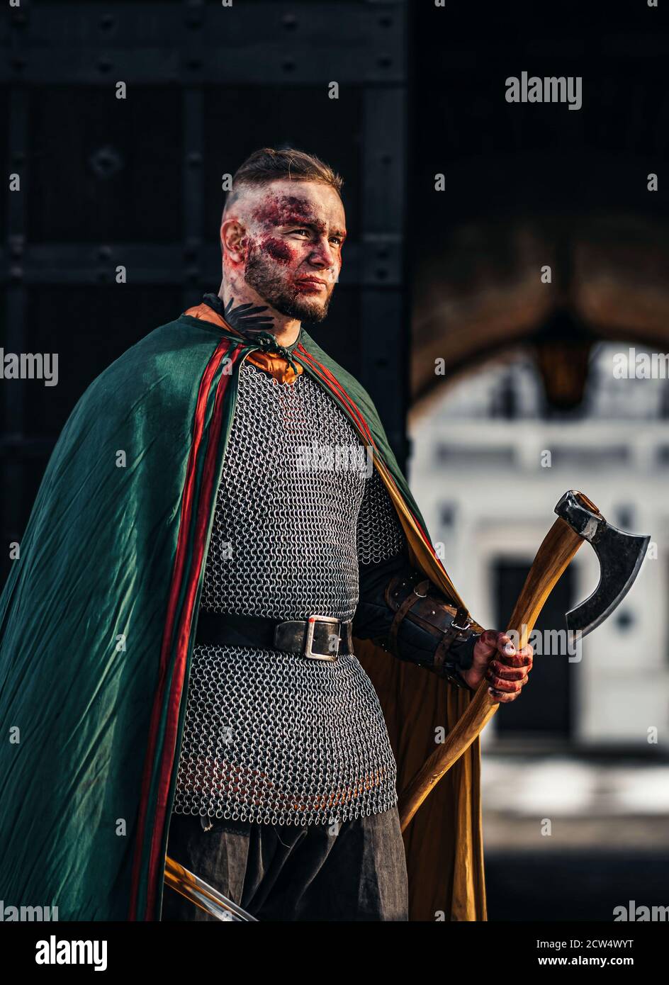 Portrait of a young medieval warrior in armor with an ax in his hands ...