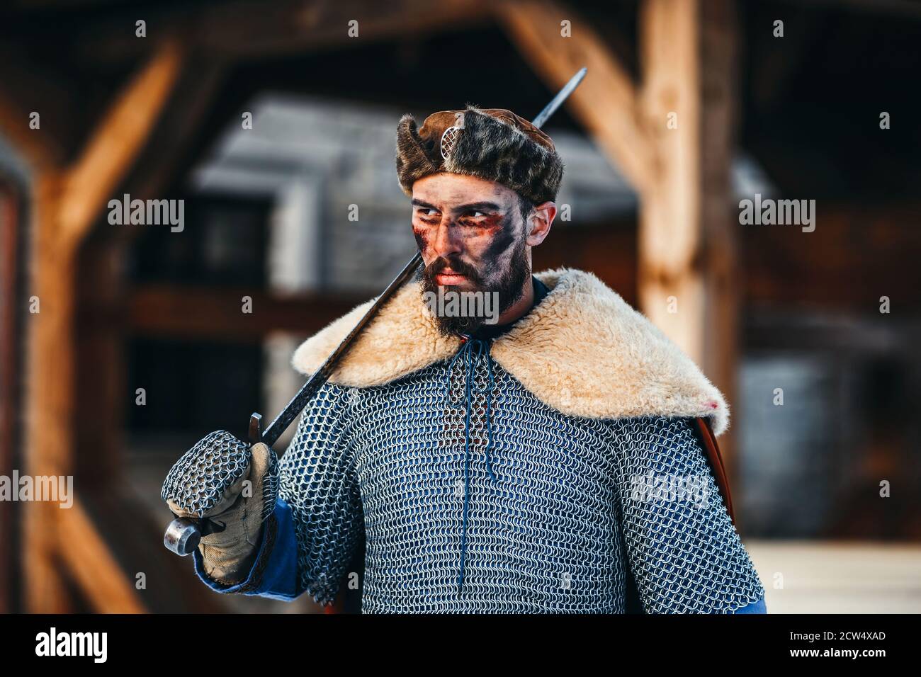 Portrait of young warrior in armor, hat and mantle after battle. A man ...