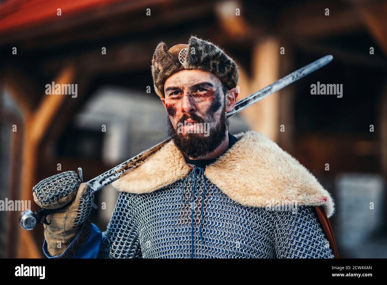 Portrait of young warrior in armor, hat and mantle after battle. A man ...