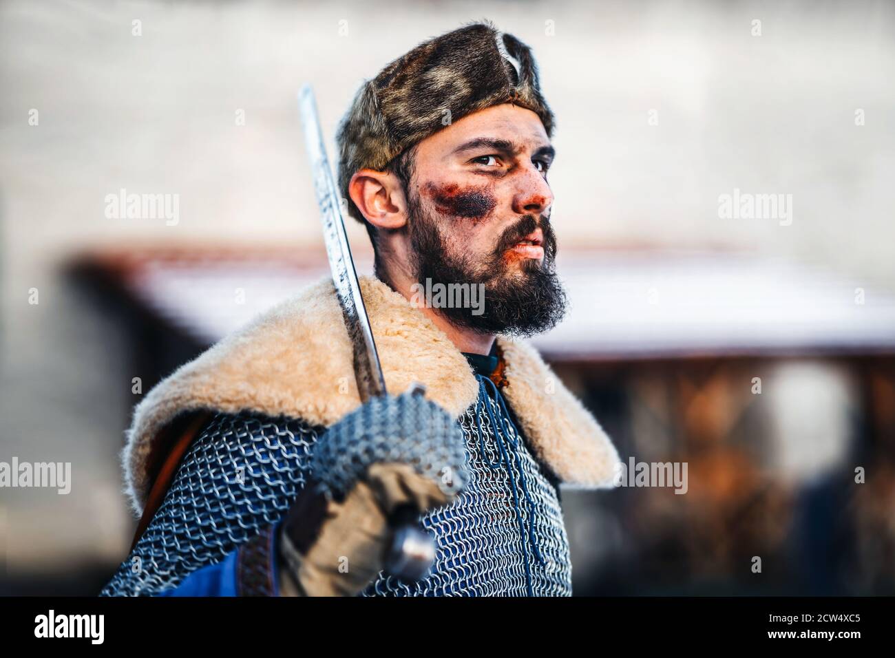 Portrait of young warrior in armor, hat and mantle after battle. A man ...