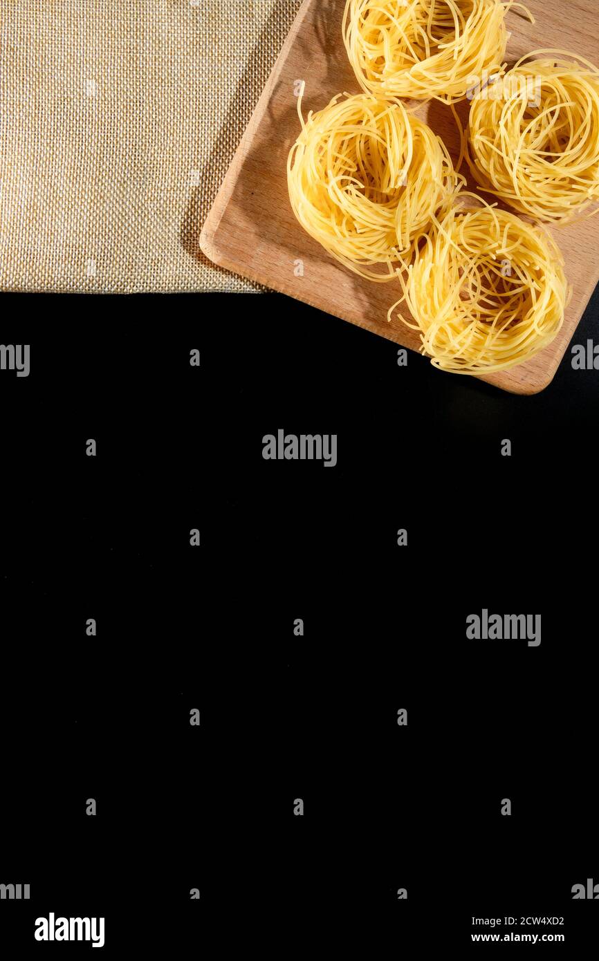 Rolled tagliatelle shape of italian pasta on black stone background ...