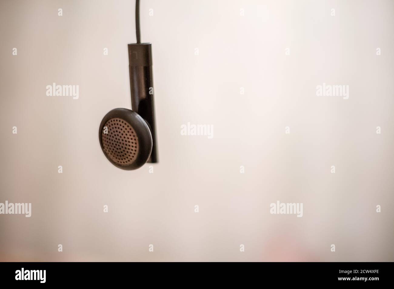 black mini headphones hanging on blurred concrete wall background Stock ...