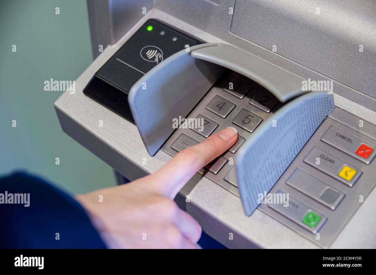 Close-up of hand entering PIN/pass code on ATM/bank machine keypad ...