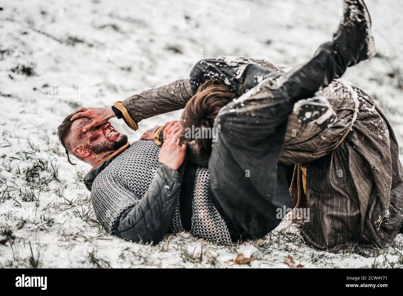 Fierce fight of two young warriors in armor on the ground in snow ...