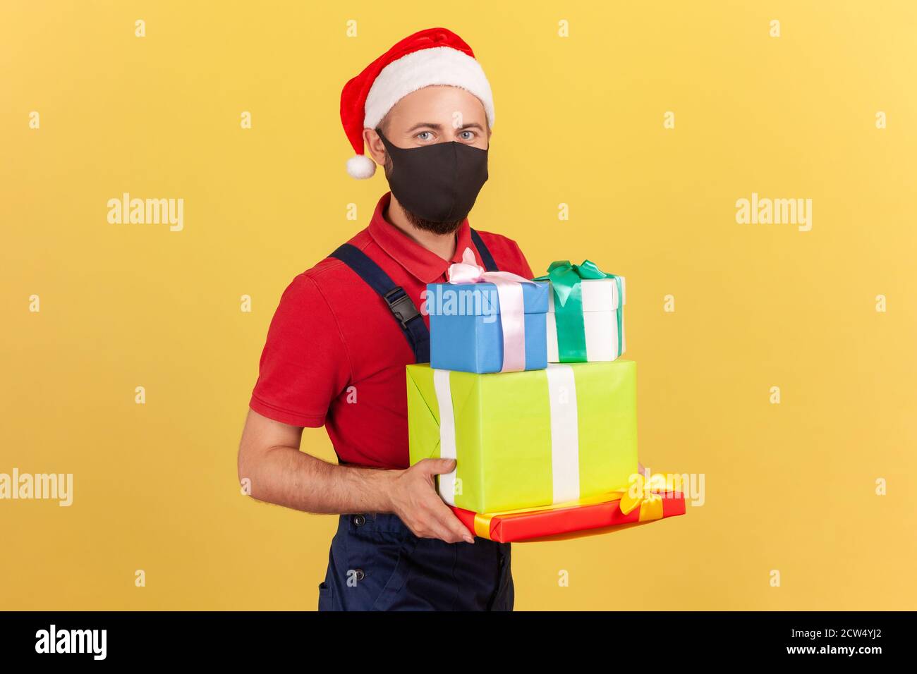 Postman in protective mask uniform and santa claus hat holding and ...