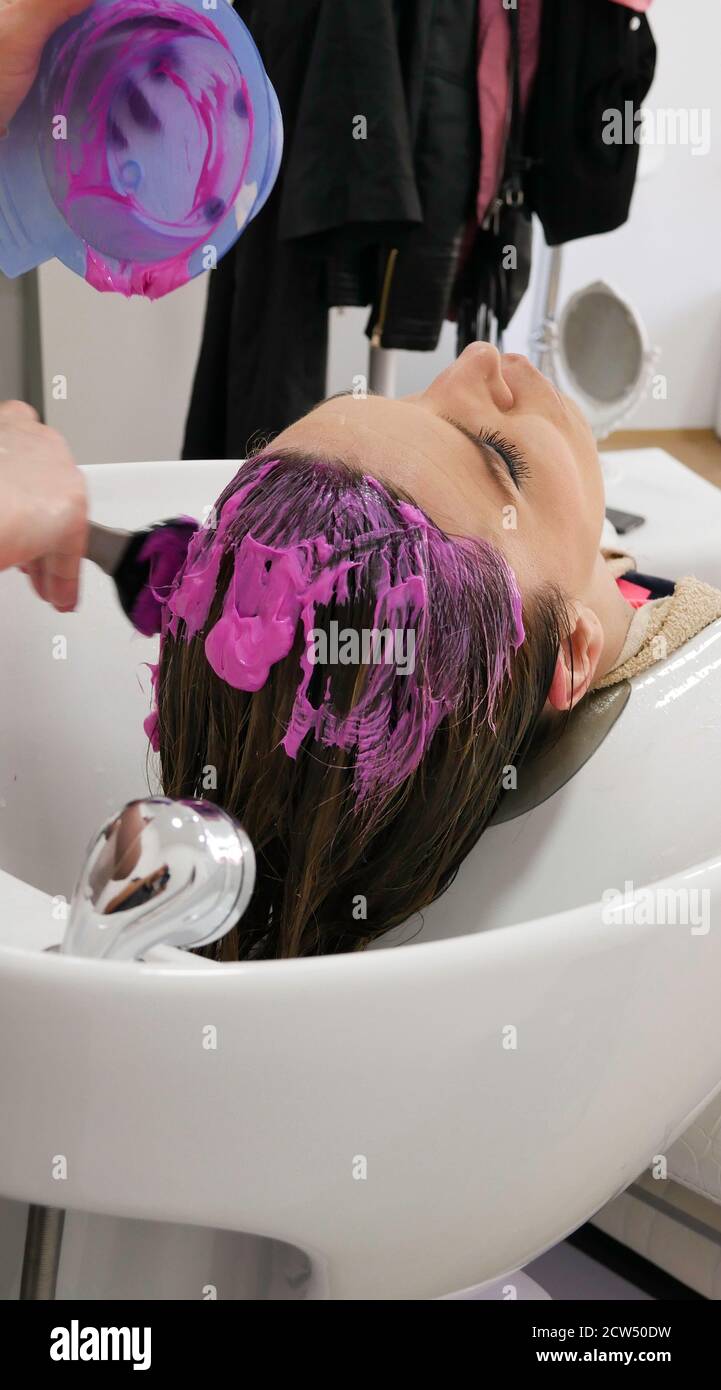 Hair treatment in a hair salon. Apply the pink mixture on the hair of ...