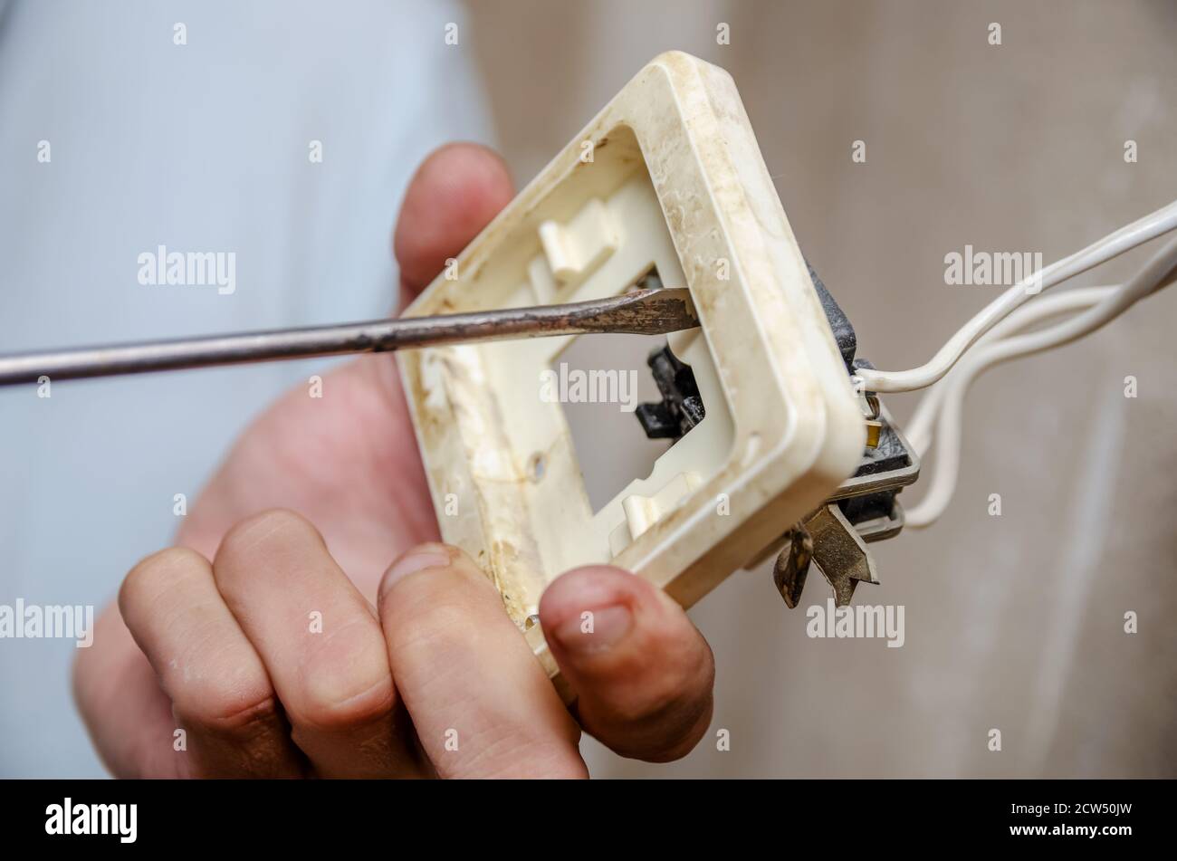 Worker man electrician is repairing damaged sockets in the apartment ...