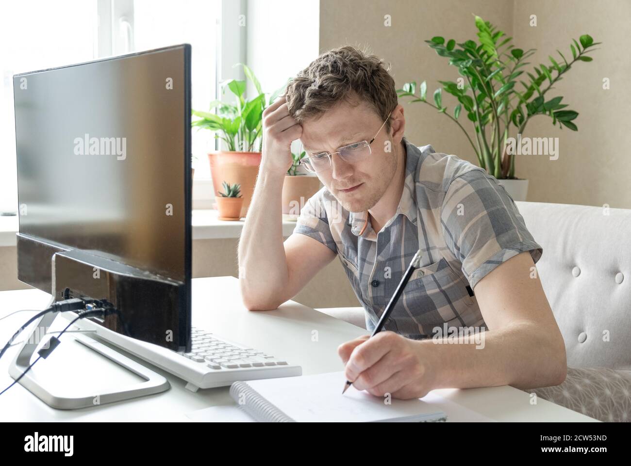 Programmer working from home, remote, home office. A man with glasses ...