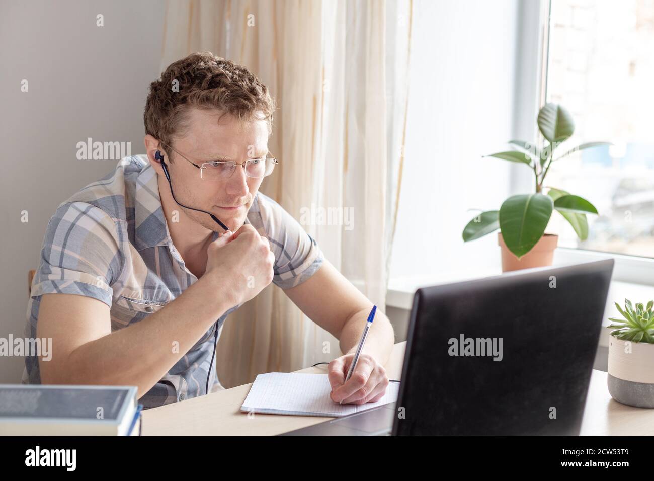 Programmer working from home, remote, home office. A man with glasses ...