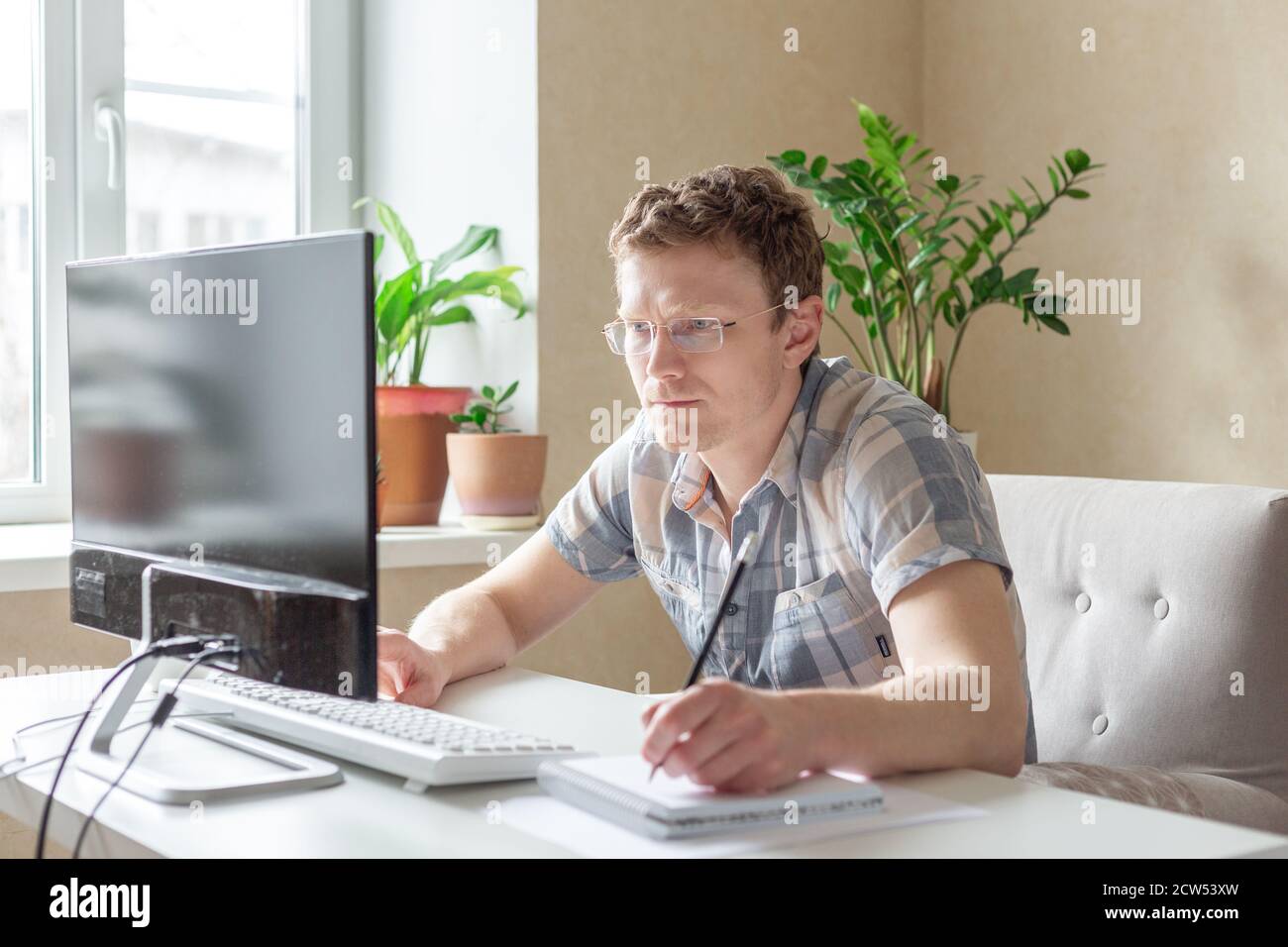 Programmer working from home, remote, home office. A man with glasses ...