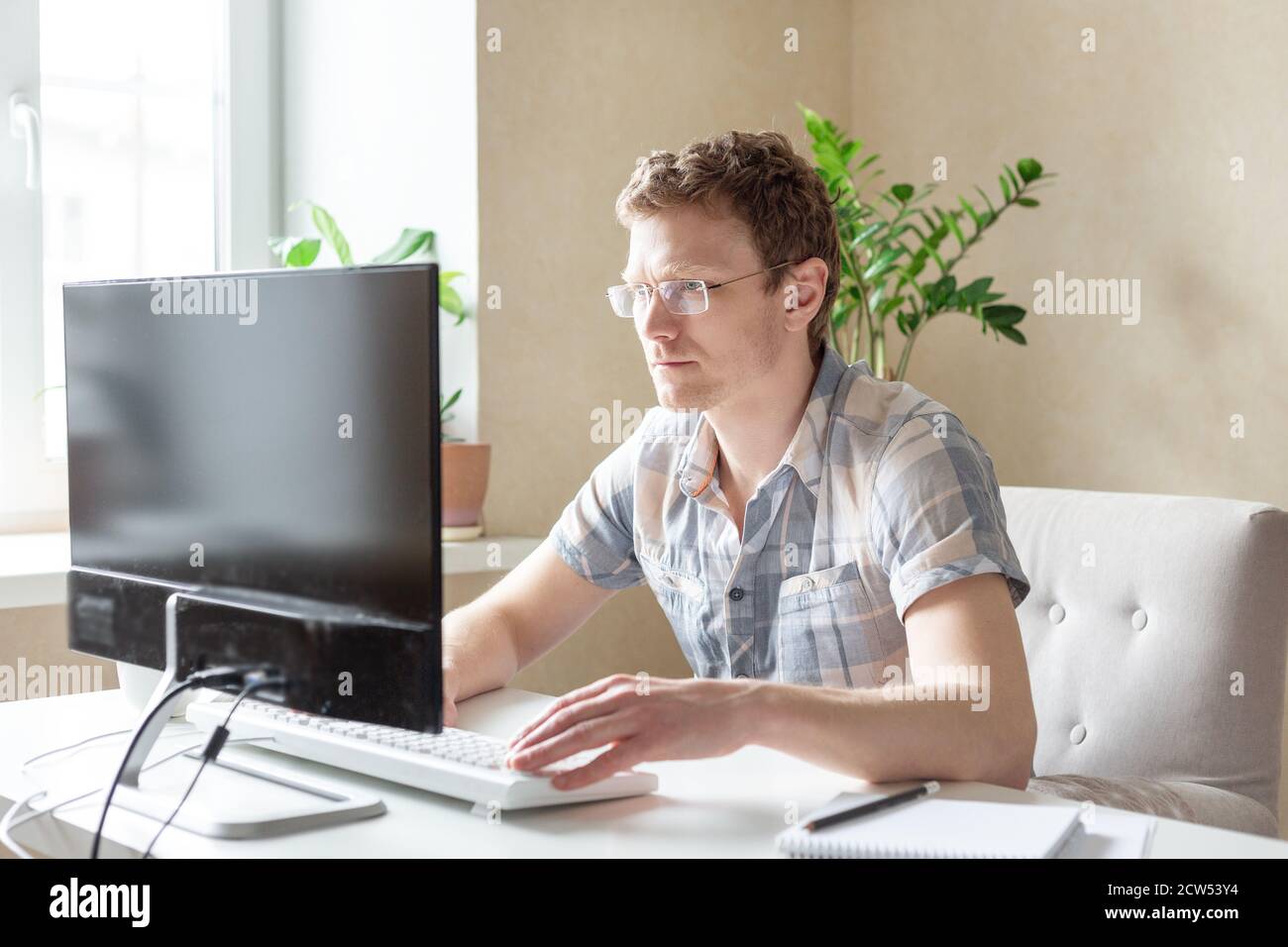Programmer working from home, remote, home office. A man with glasses ...