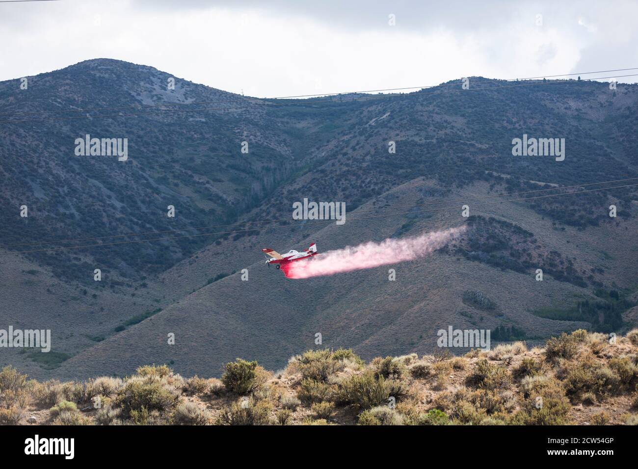 Small red and white plane just beginning to drop fire retardant on a ...