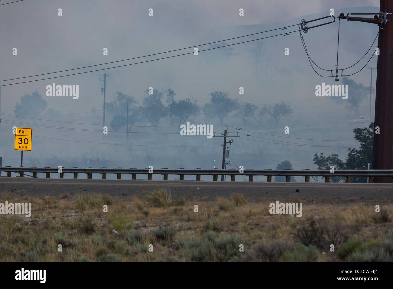 Emergency fire vehicle barely visible through the smoke of a wildfire ...