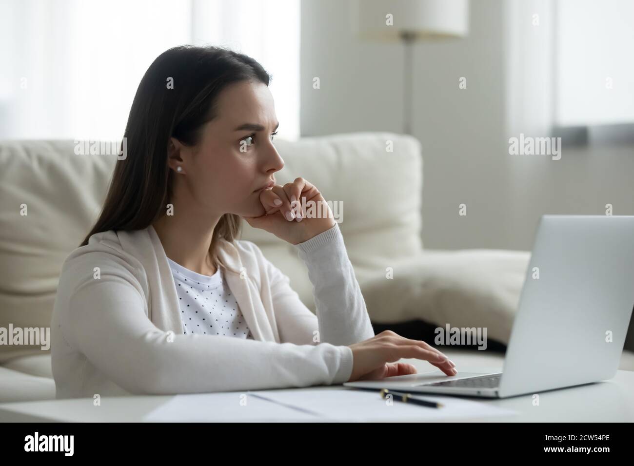 Pensive young woman work on laptop thinking Stock Photo - Alamy