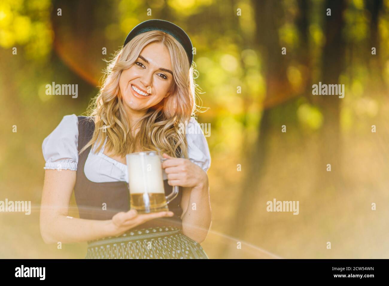 Pretty happy blonde in dirndl, traditional festival dress, holding mug ...