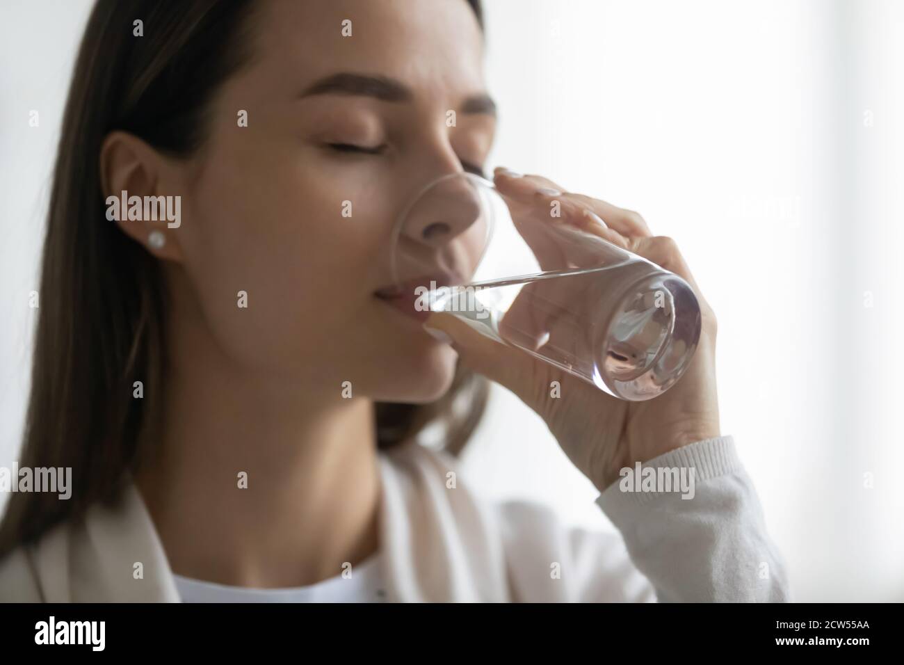 Thirsty female enjoy pure mineral water from glass Stock Photo - Alamy
