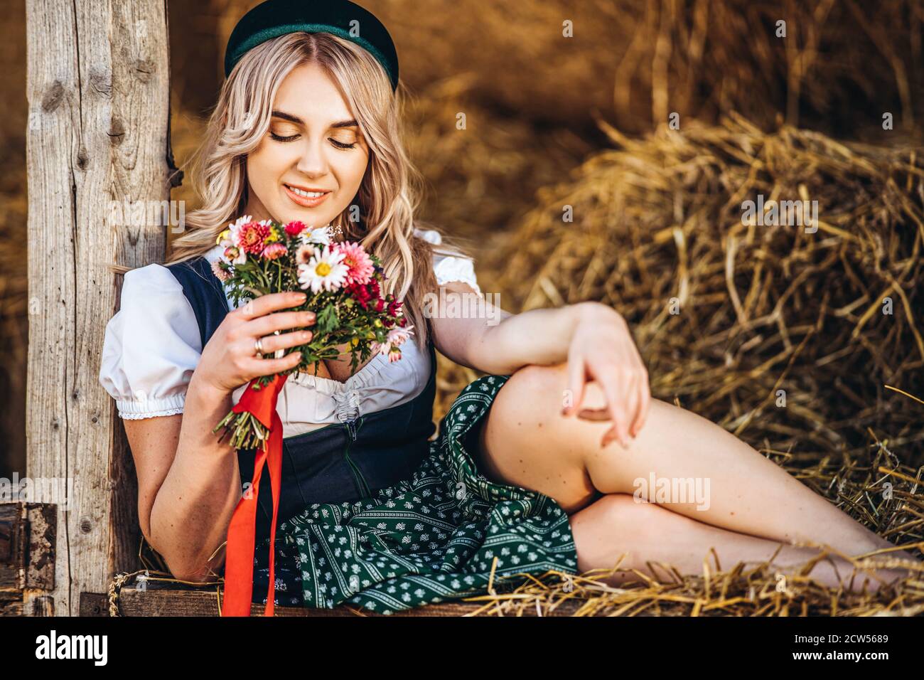Cute blonde in dirndl, traditional festival dress with bouquet of field ...