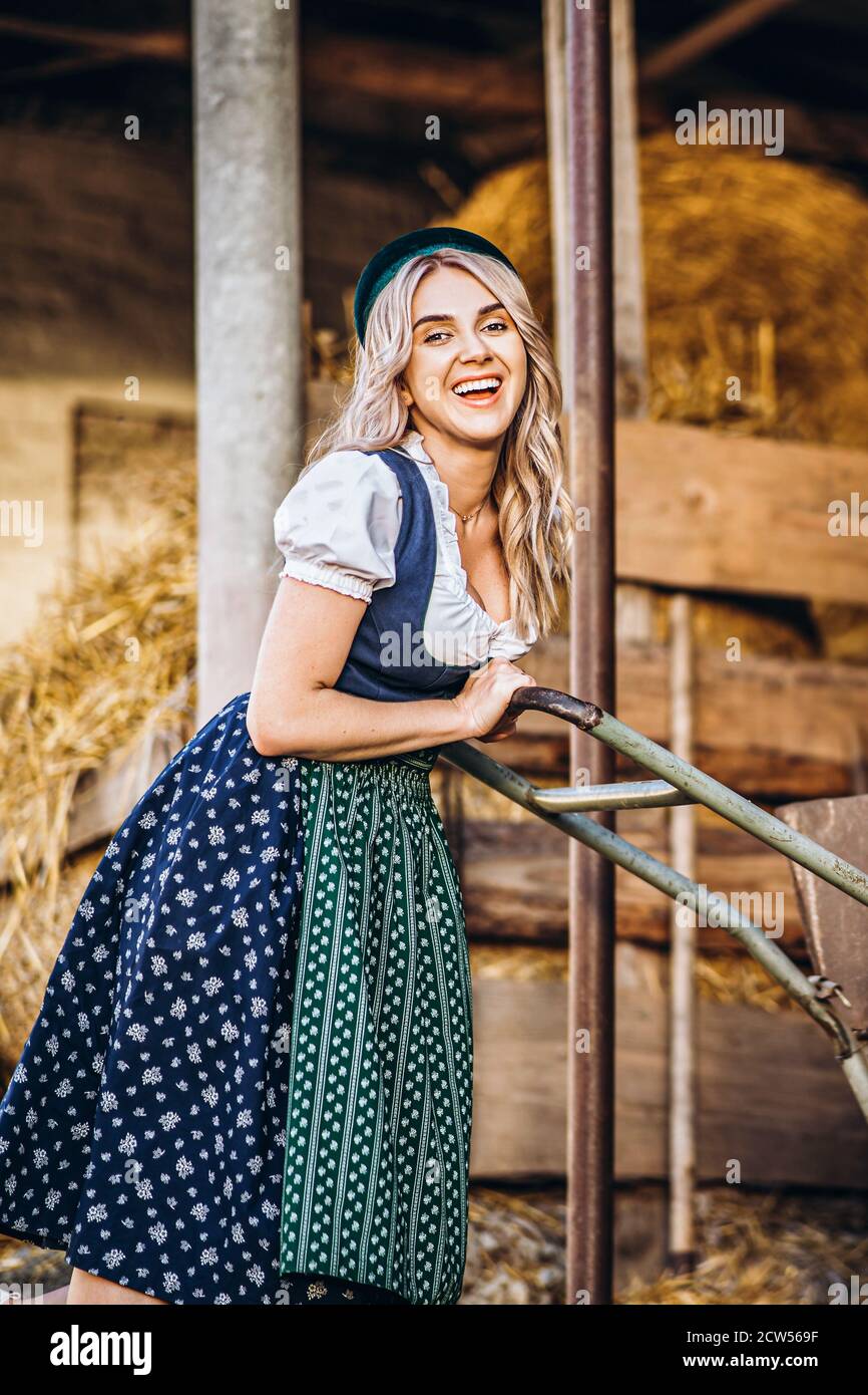 Pretty smiling blonde in traditional dress with wheelbarrow working in ...