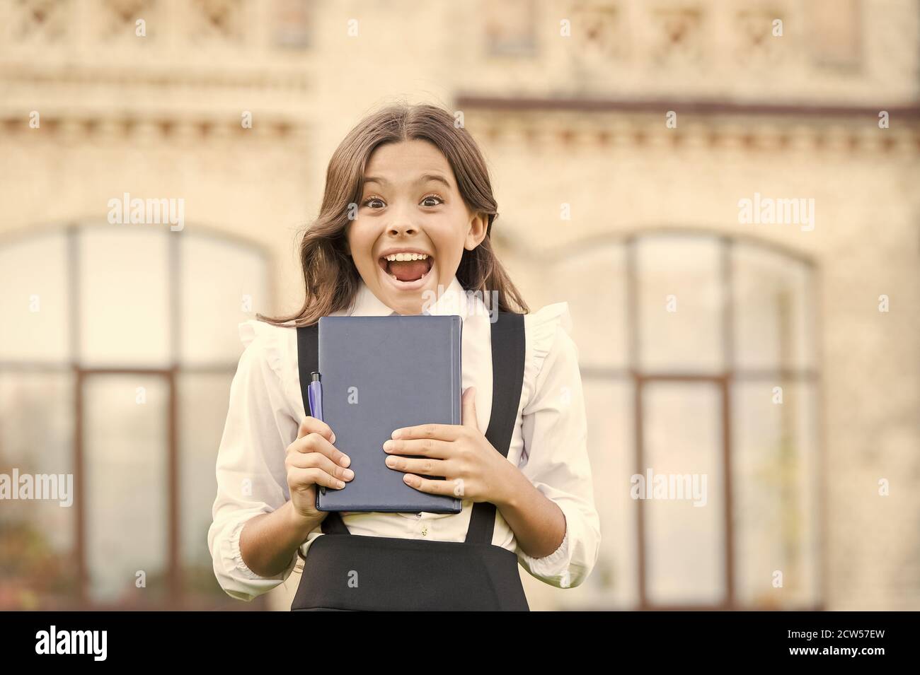 Excited about studying. School education concept. Cute smiling child hold book. Little girl ...