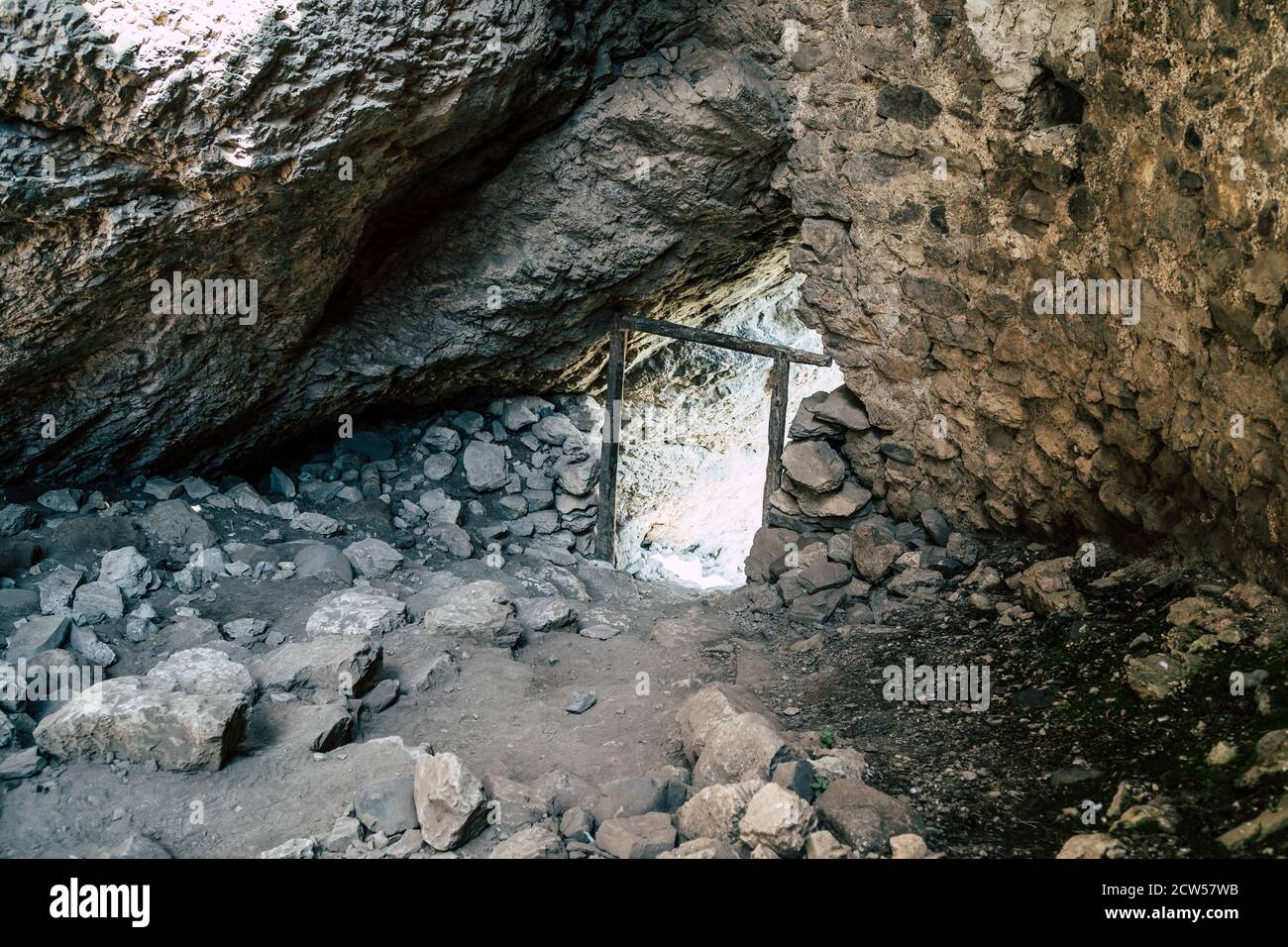 Entrance from inside to ancient stone cave located in rock. Destroyed ...
