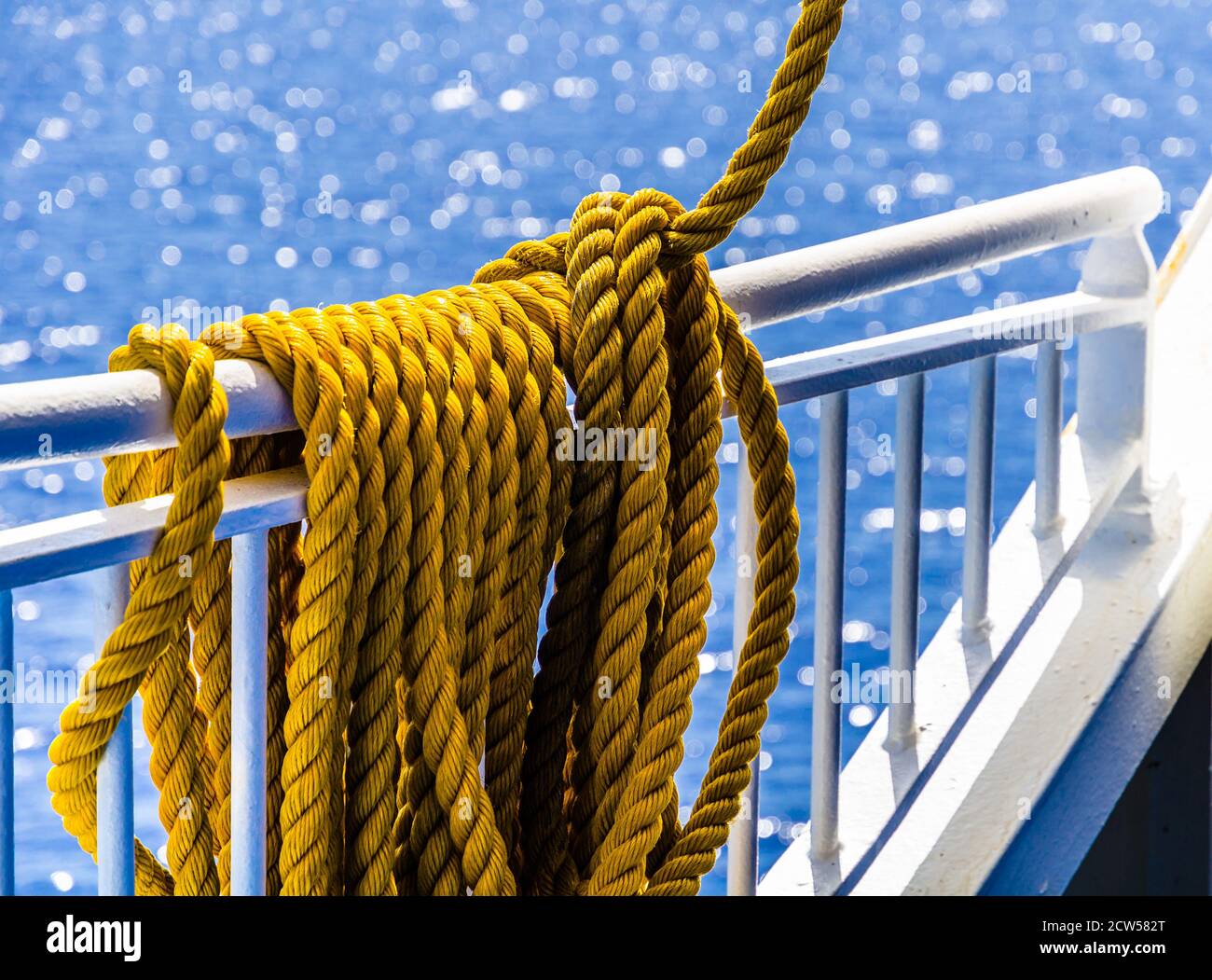 Yellow braided rope draped over a ship railing Stock Photo - Alamy