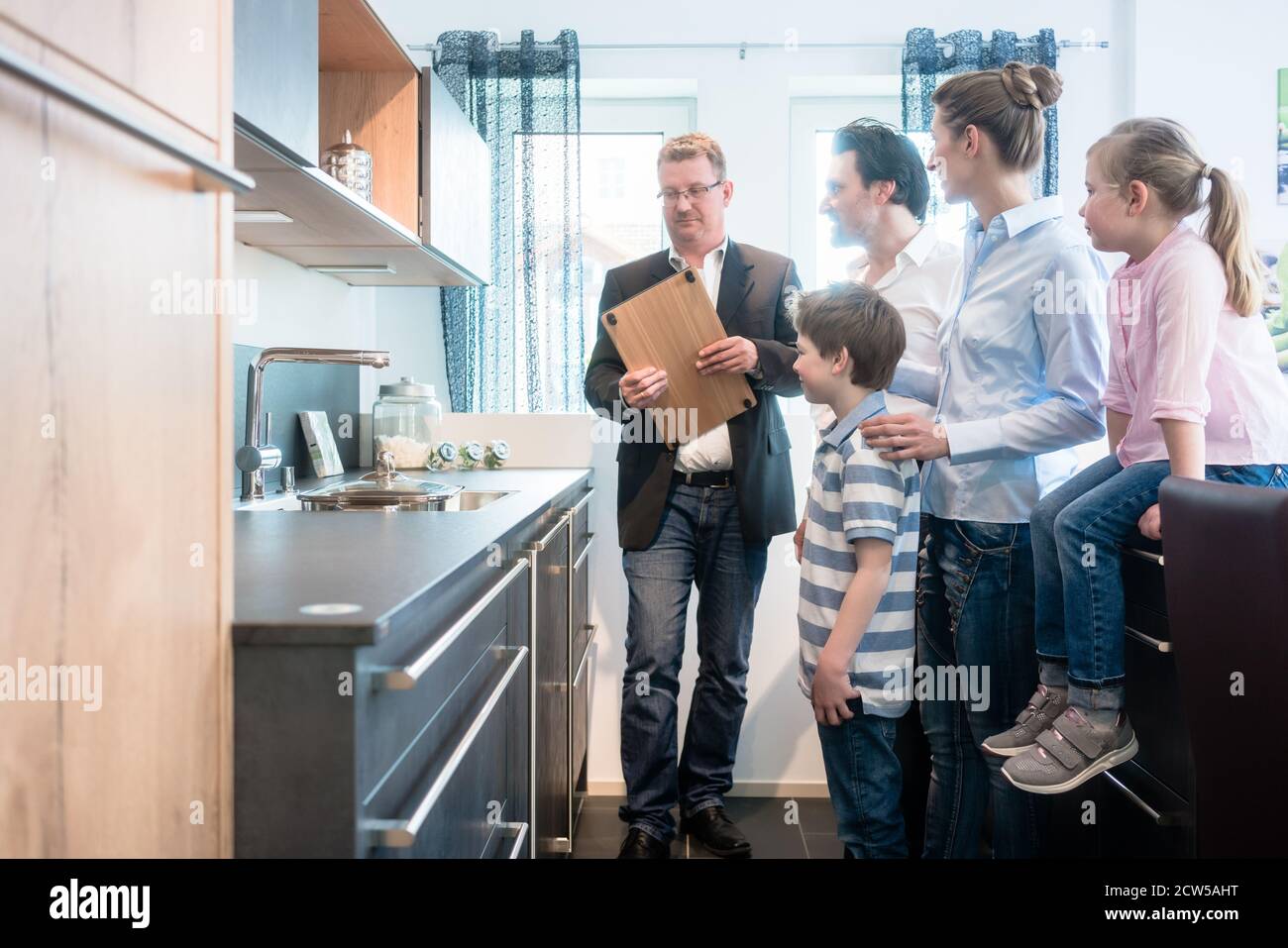 Salesman showing family the features of a new kitchen Stock Photo - Alamy