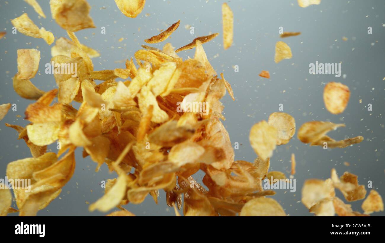 Flying potatoes chips up in the air in freeze motion. Isolated on grey ...