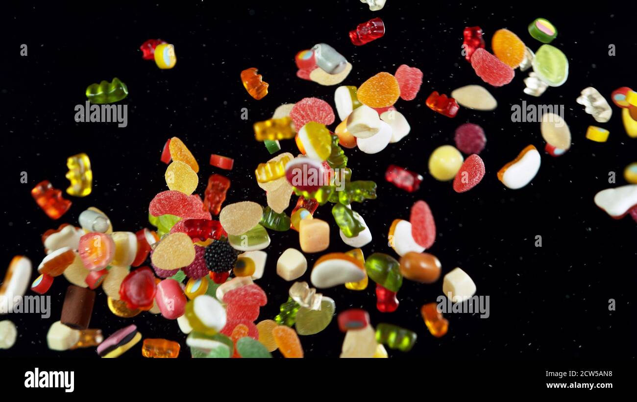 Freeze motion of flying candies up in the air. Isolated on black ...