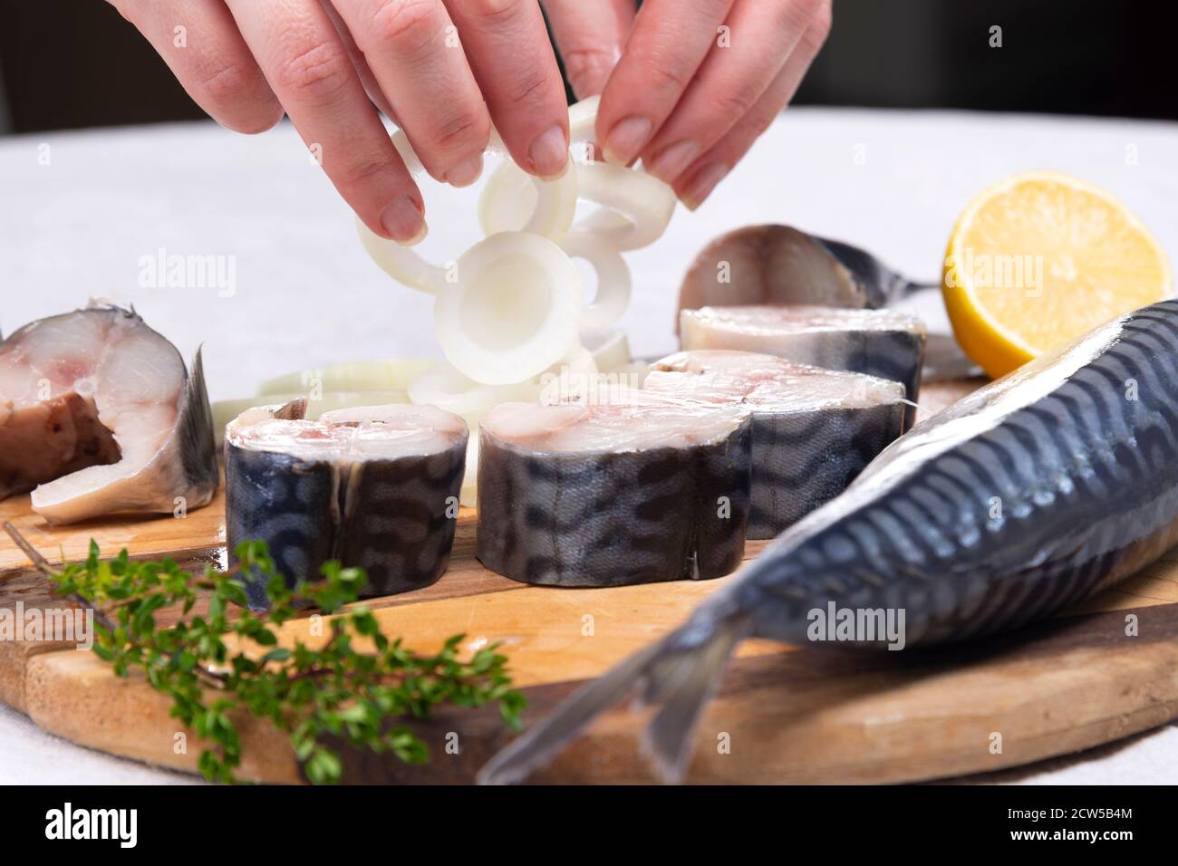 the chef's hand sprinkles onions on mackerel with lemon Stock Photo - Alamy