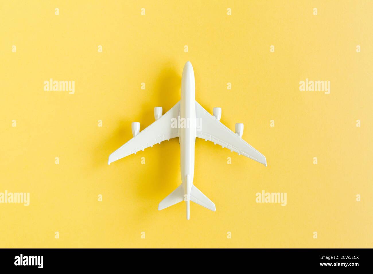 White model plane, airplane on yellow background. Top view, flat lay ...
