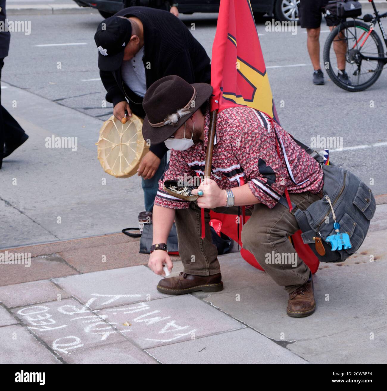 First Nation protester holding warrior flag writing chalk message on ...